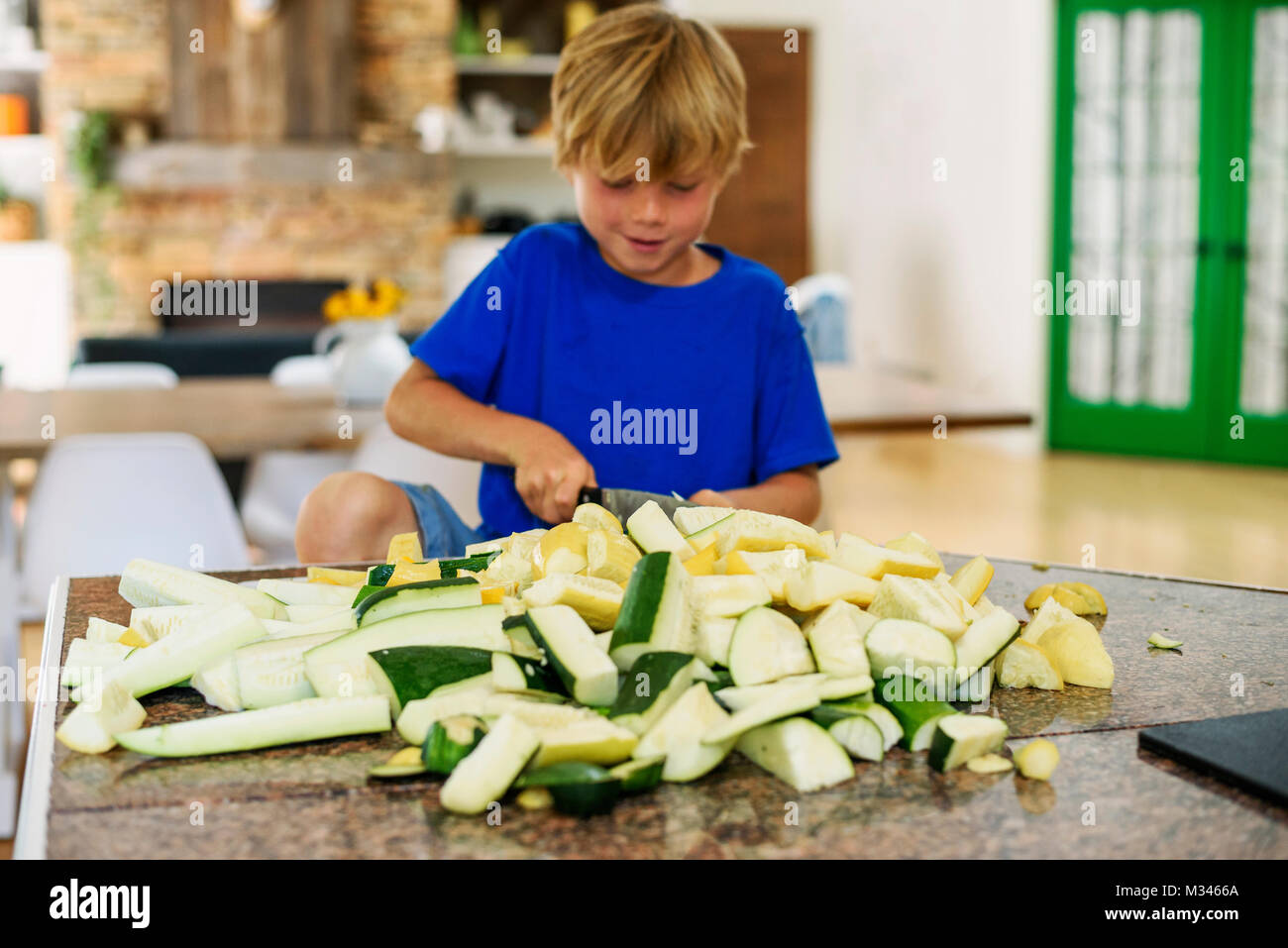 Boy standing in kitchen chopping squash Stock Photo - Alamy
