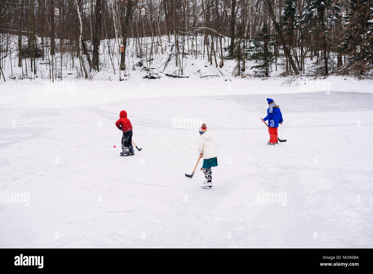 Three children playing ice hockey Stock Photo - Alamy