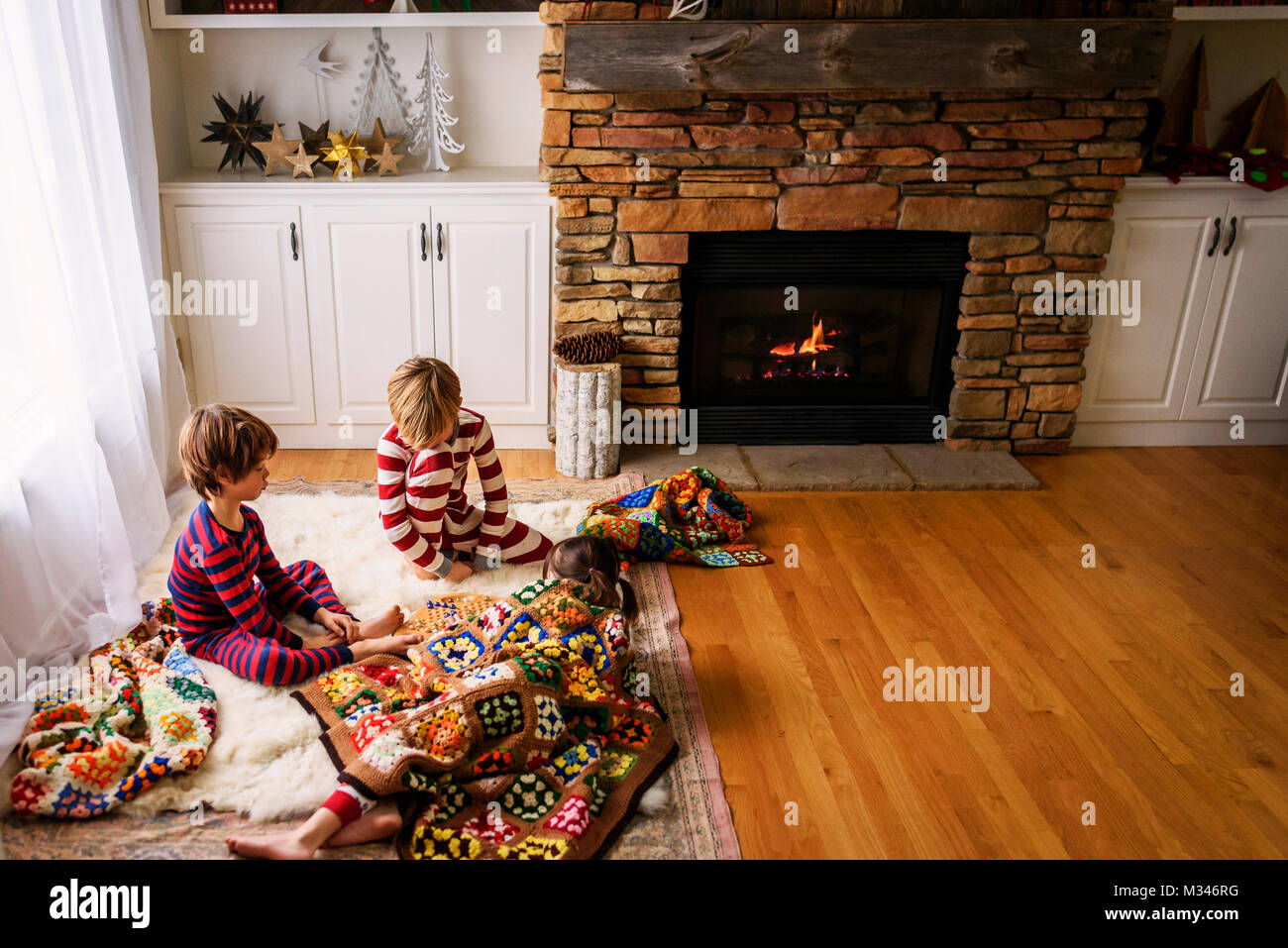 Three children inside playing a board game Stock Photo - Alamy