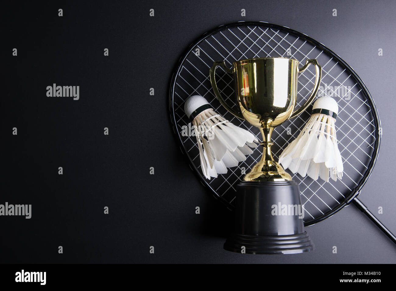 Golden trophy, Shuttlecocks and badminton racket on black background ...