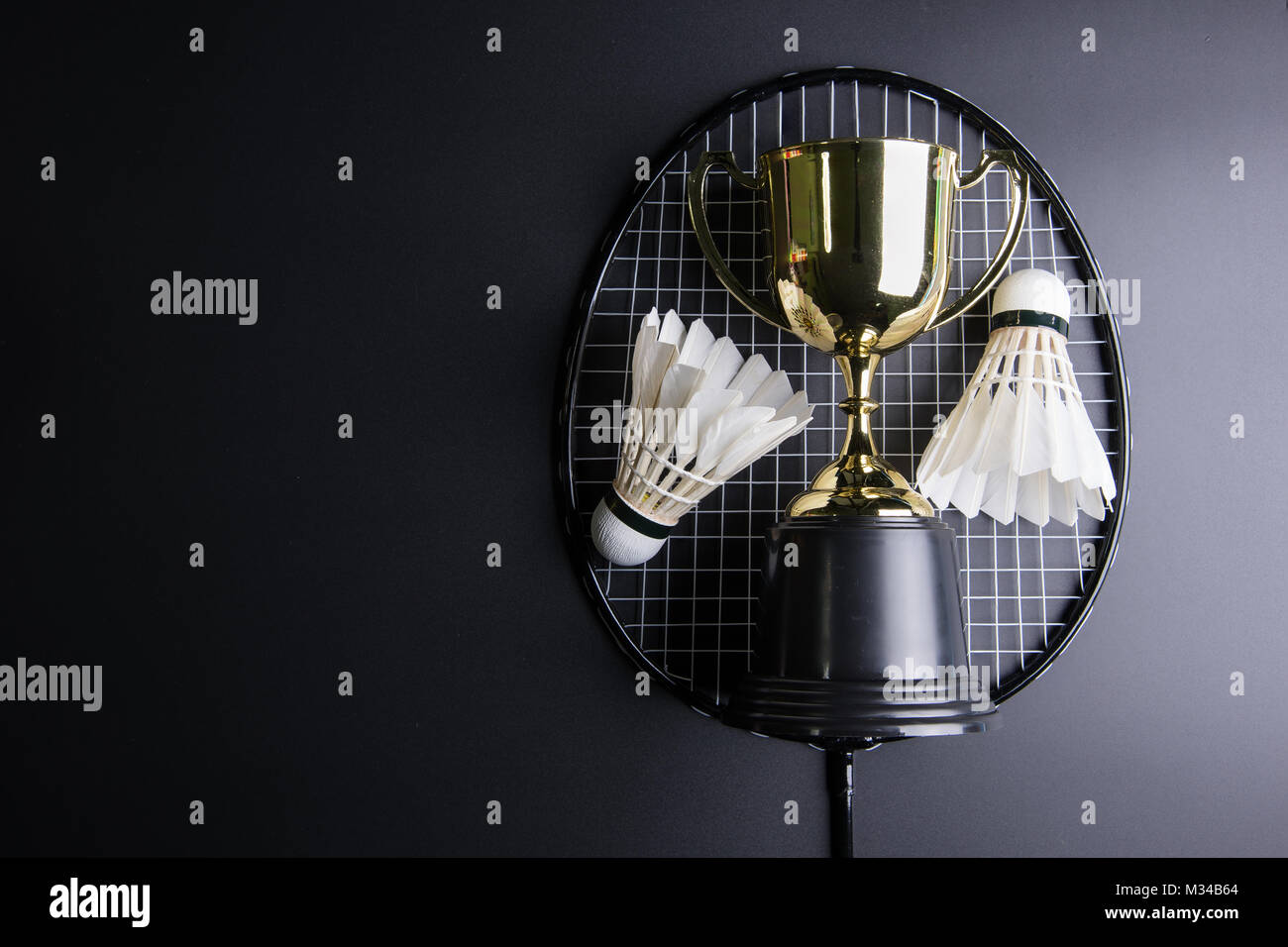 Golden trophy, Shuttlecocks and badminton racket on black background ...