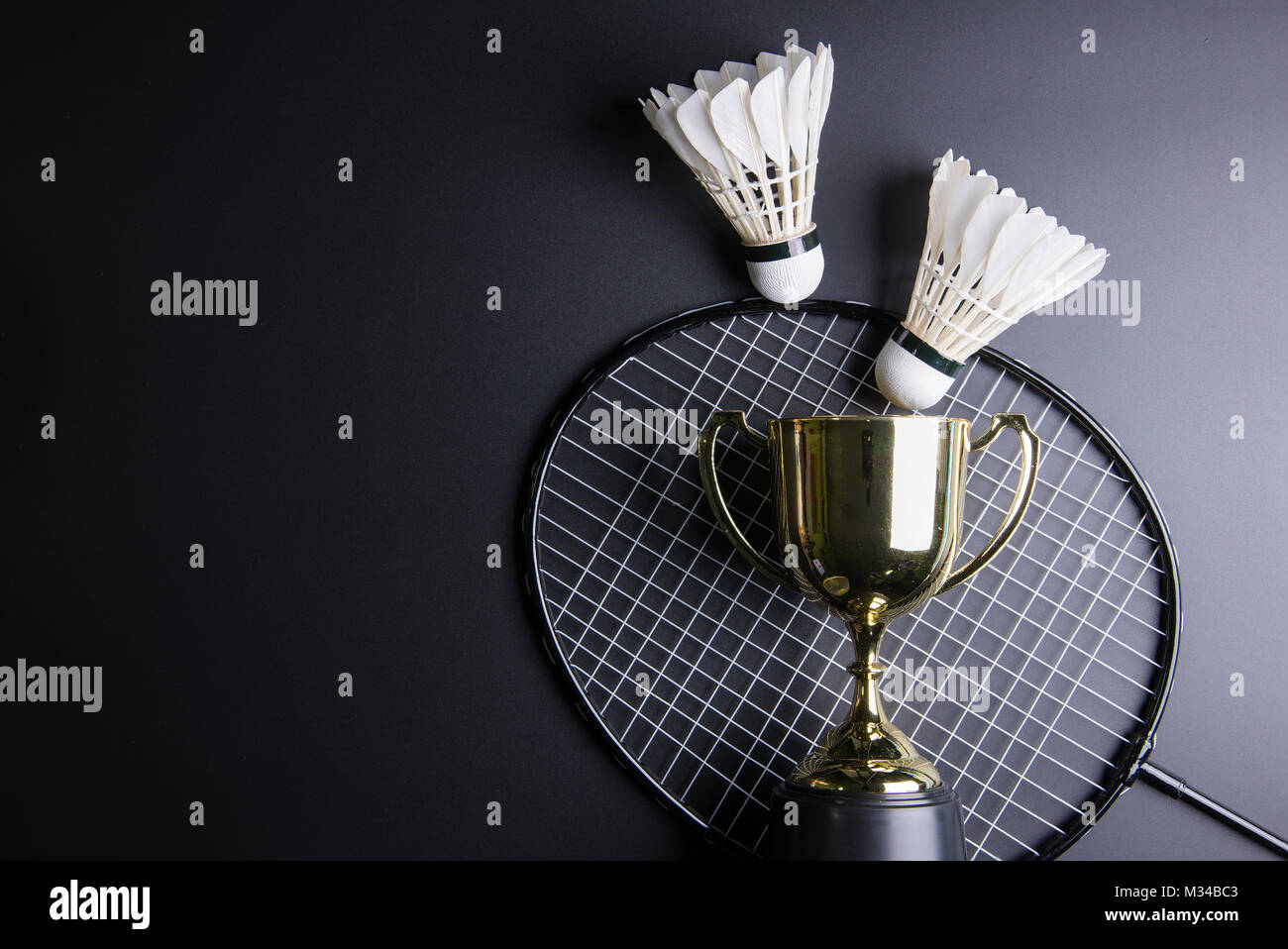 Golden trophy, Shuttlecocks and badminton racket on black background ...