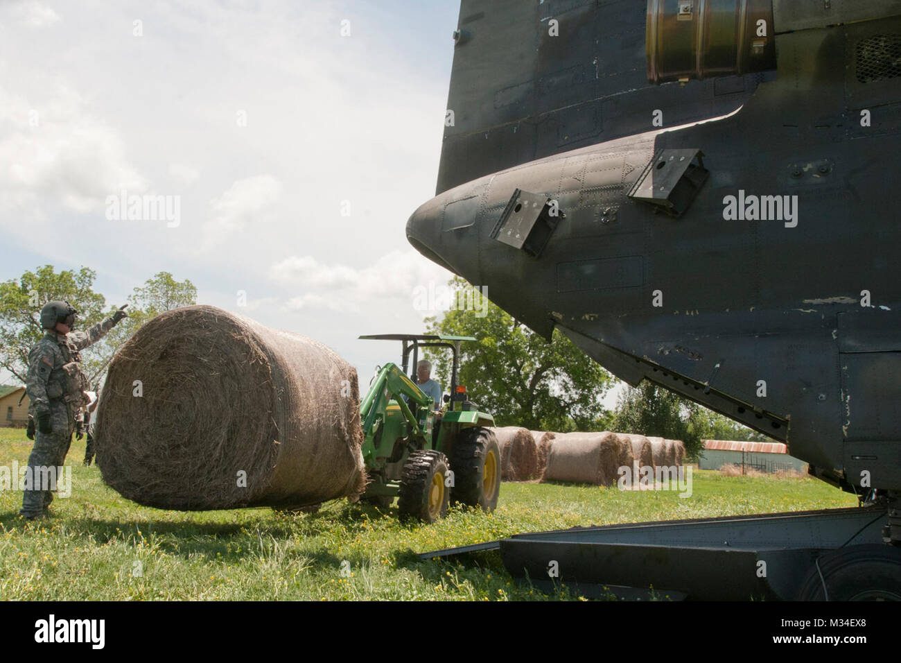 A 1,200 pound round bale of hay is moved into position as it is ...