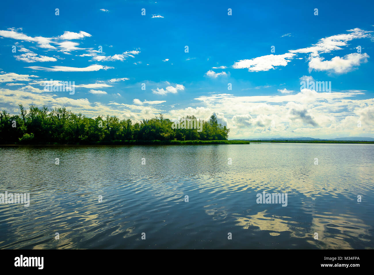 Wide angle lake landscape with trees, forest and clouds in the ...