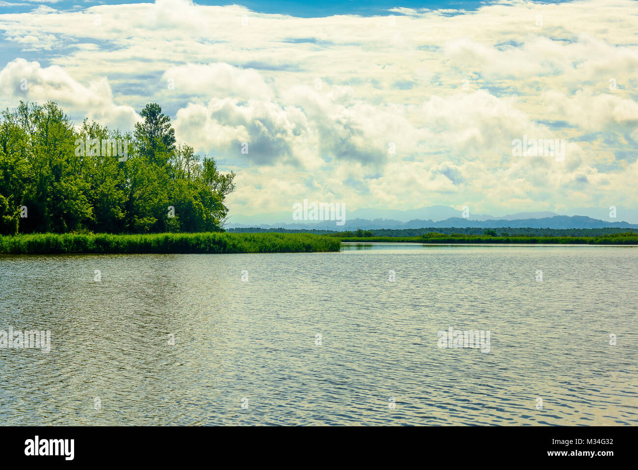Wide angle lake landscape with trees, forest and clouds in the ...