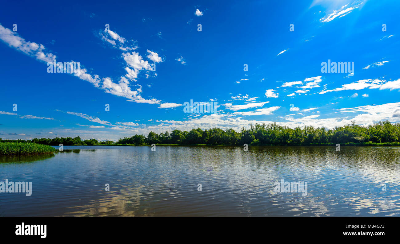Wide angle lake landscape with trees, forest and clouds in the ...