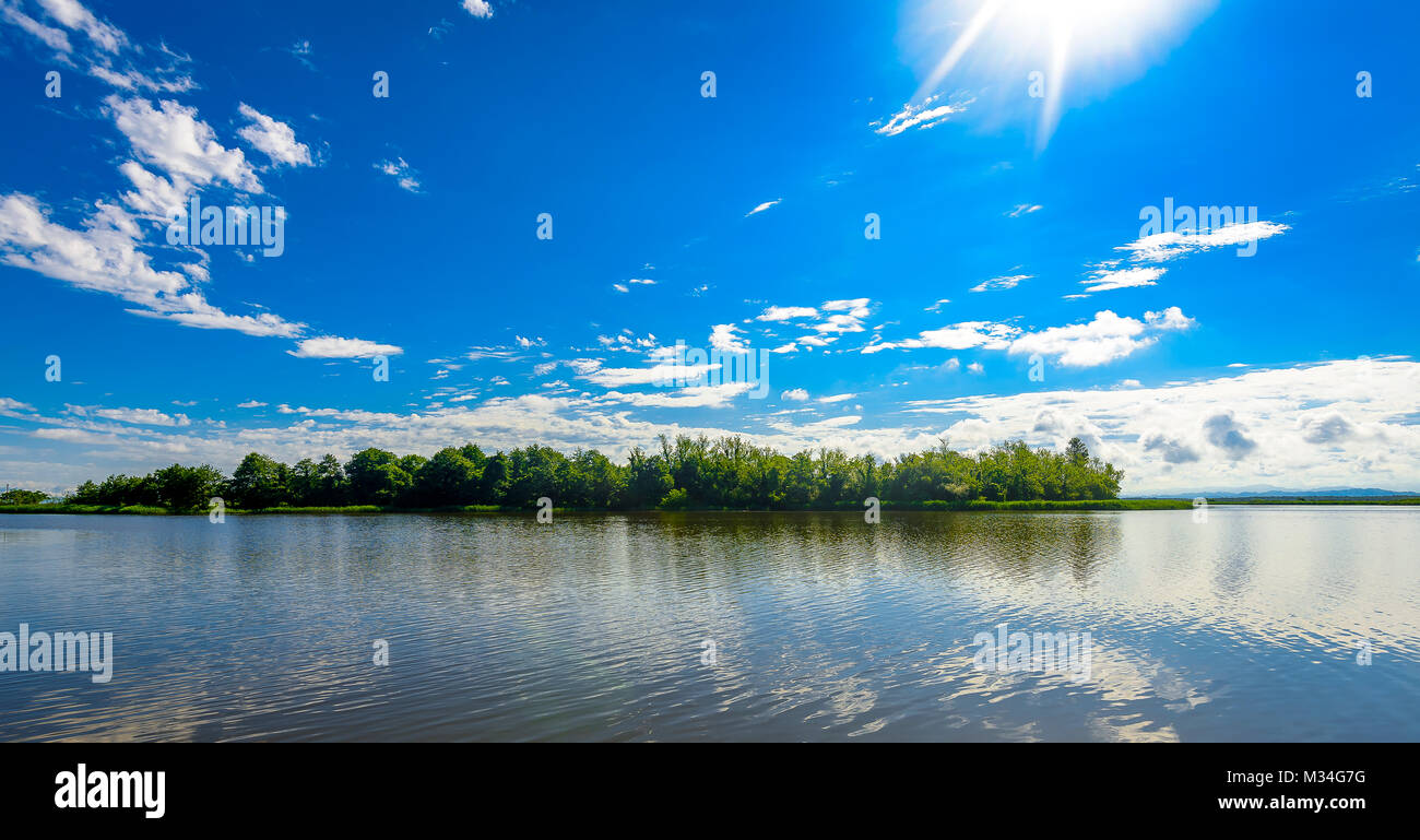 Wide angle lake landscape with trees, forest and clouds in the ...