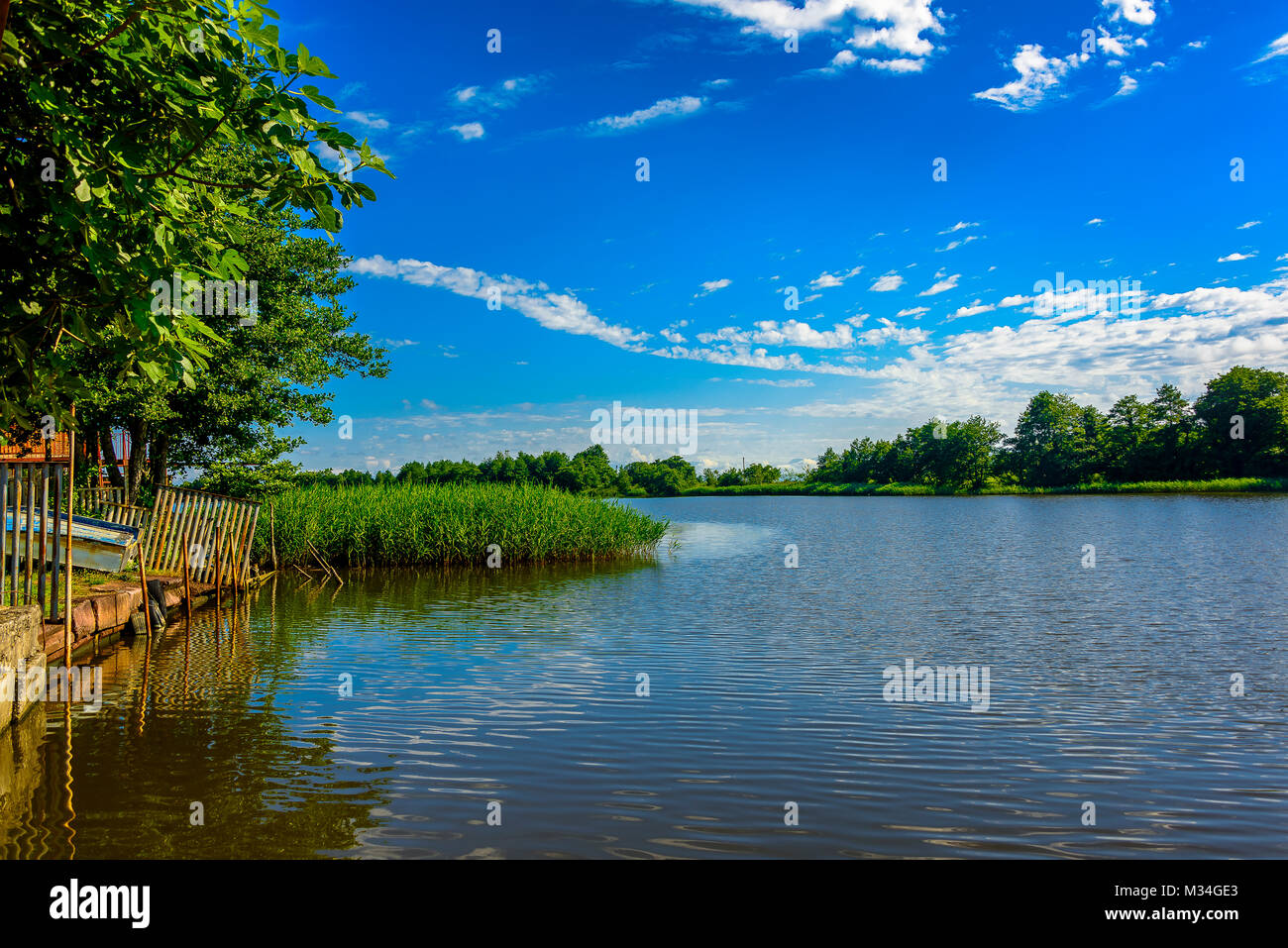 Wide angle lake landscape with trees, forest and clouds in the ...
