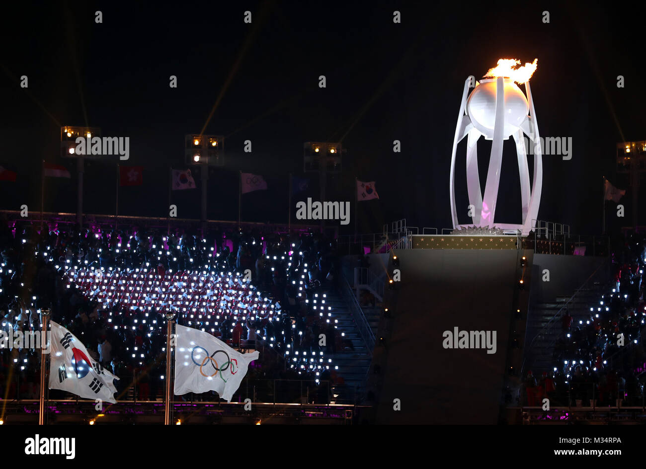 The olympic torch is lit during the ceremony hi-res stock photography ...