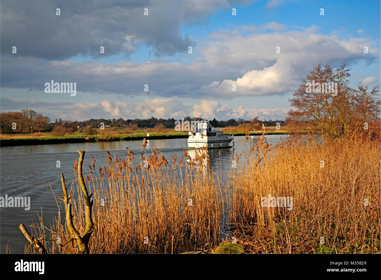 A boat cruising on the River Yare on the Norfolk Broads in winter at ...