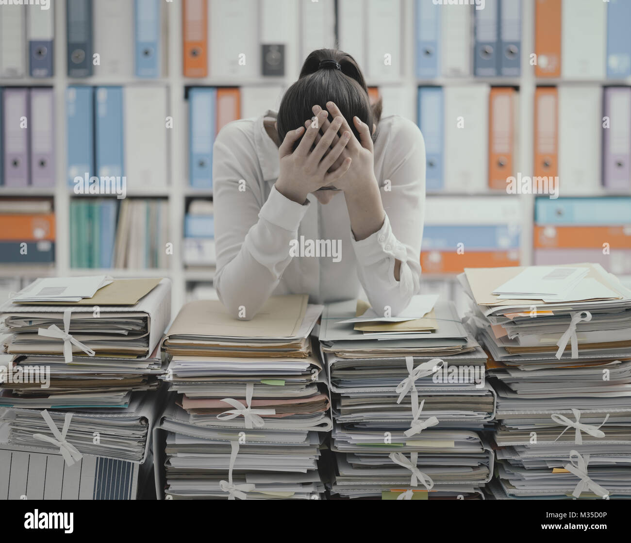 Frustrated you office worker leaning on piles of paperwork, she is ...