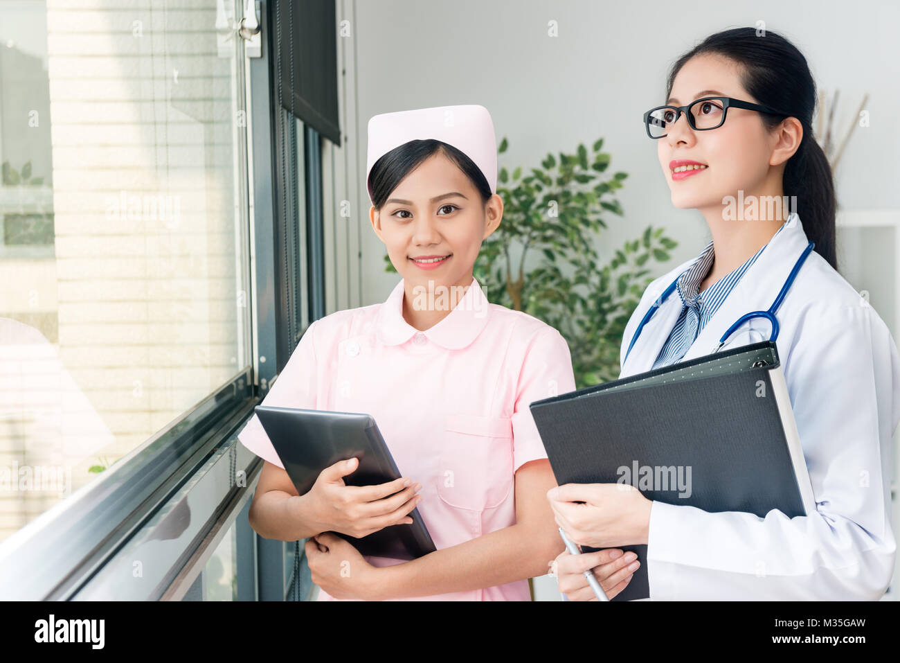 confident young nurse holding mobile pad computer looking at camera and ...