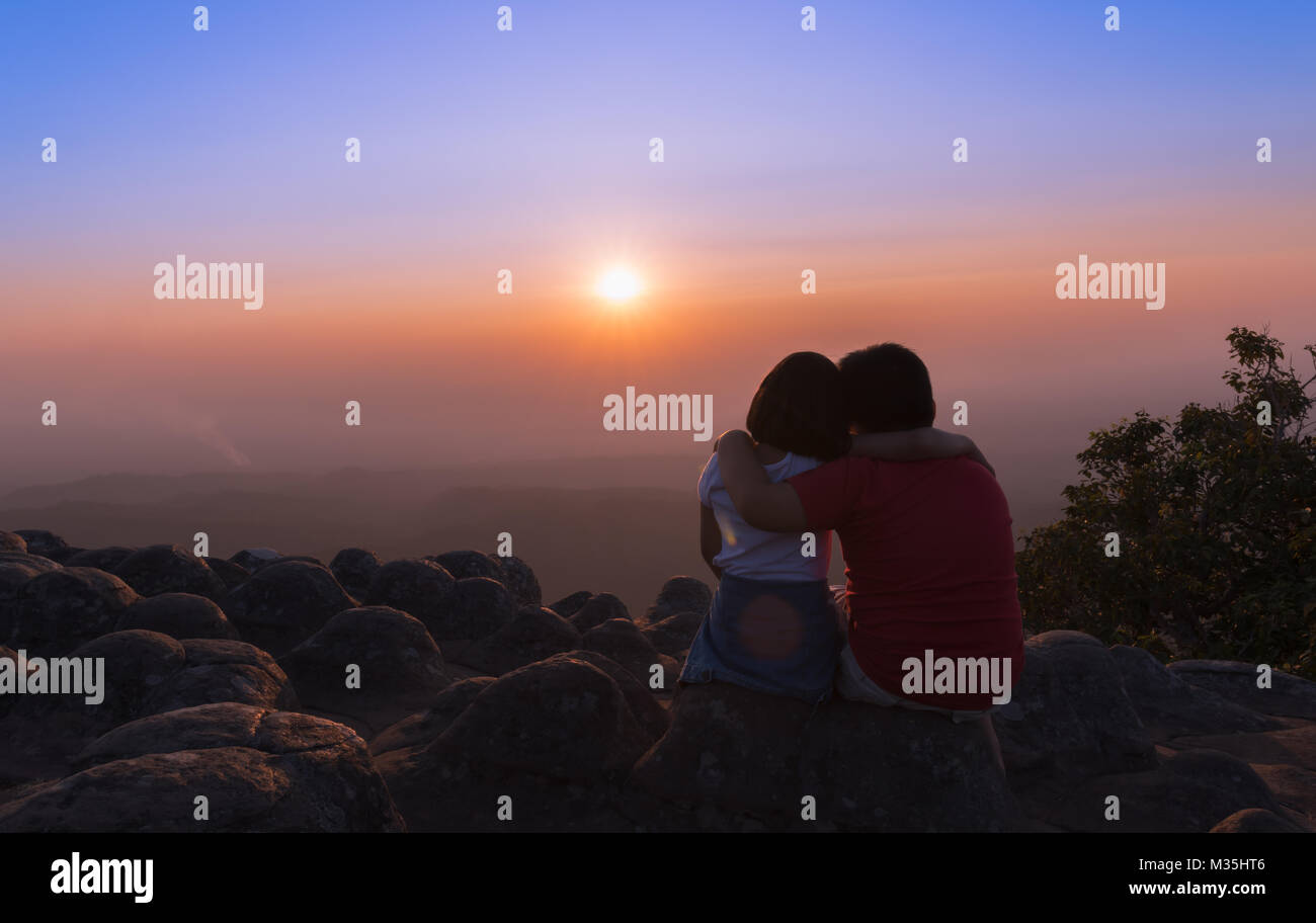 brother and sister sitting on rock and see sunset together at sunset ...