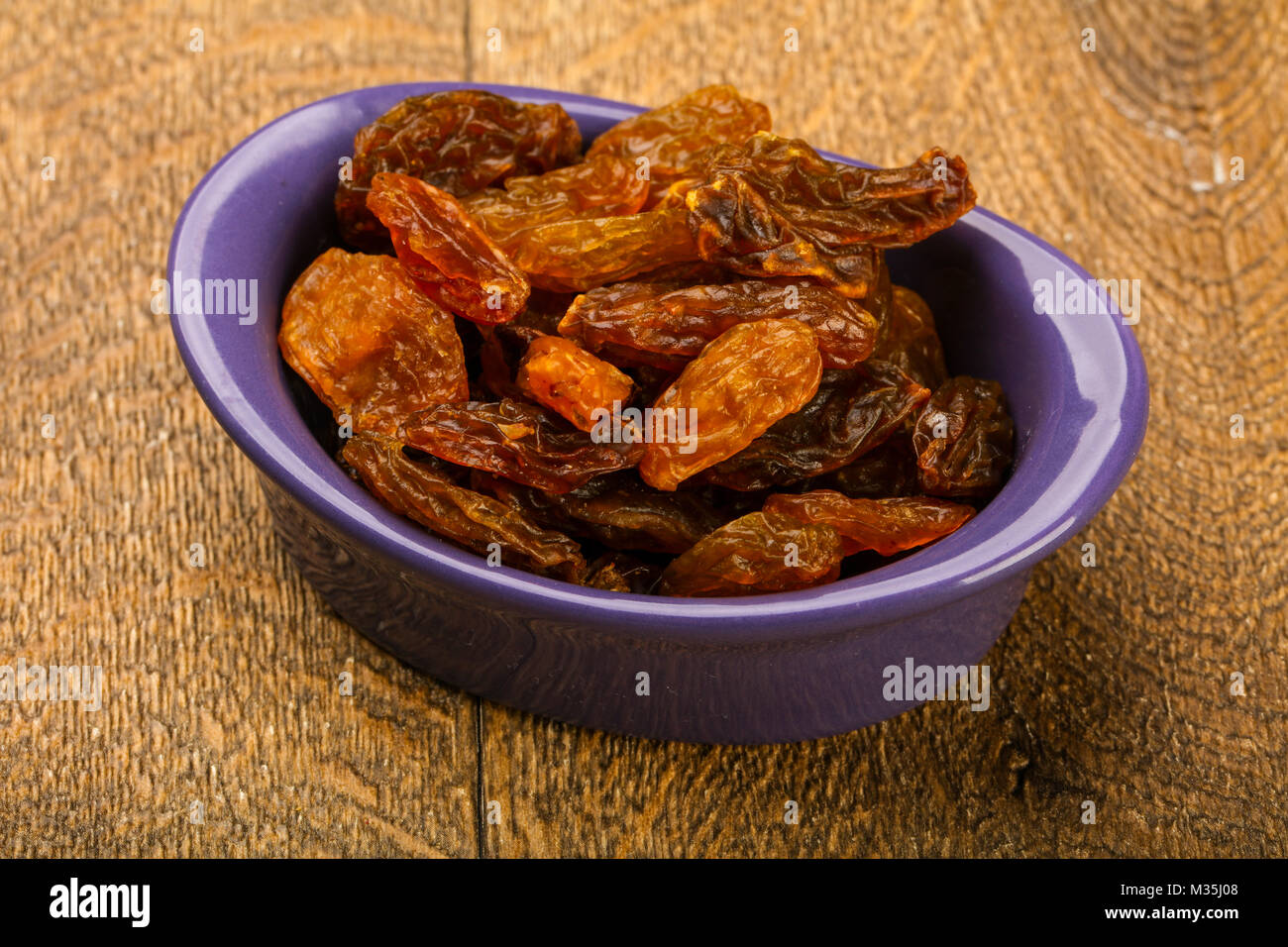 Dry Raisin in the bowl over the wooden background Stock Photo - Alamy