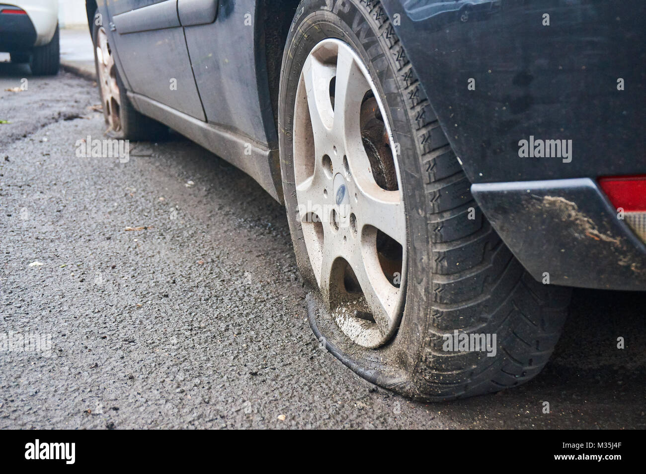 Parked car with both tyres deflated Stock Photo - Alamy