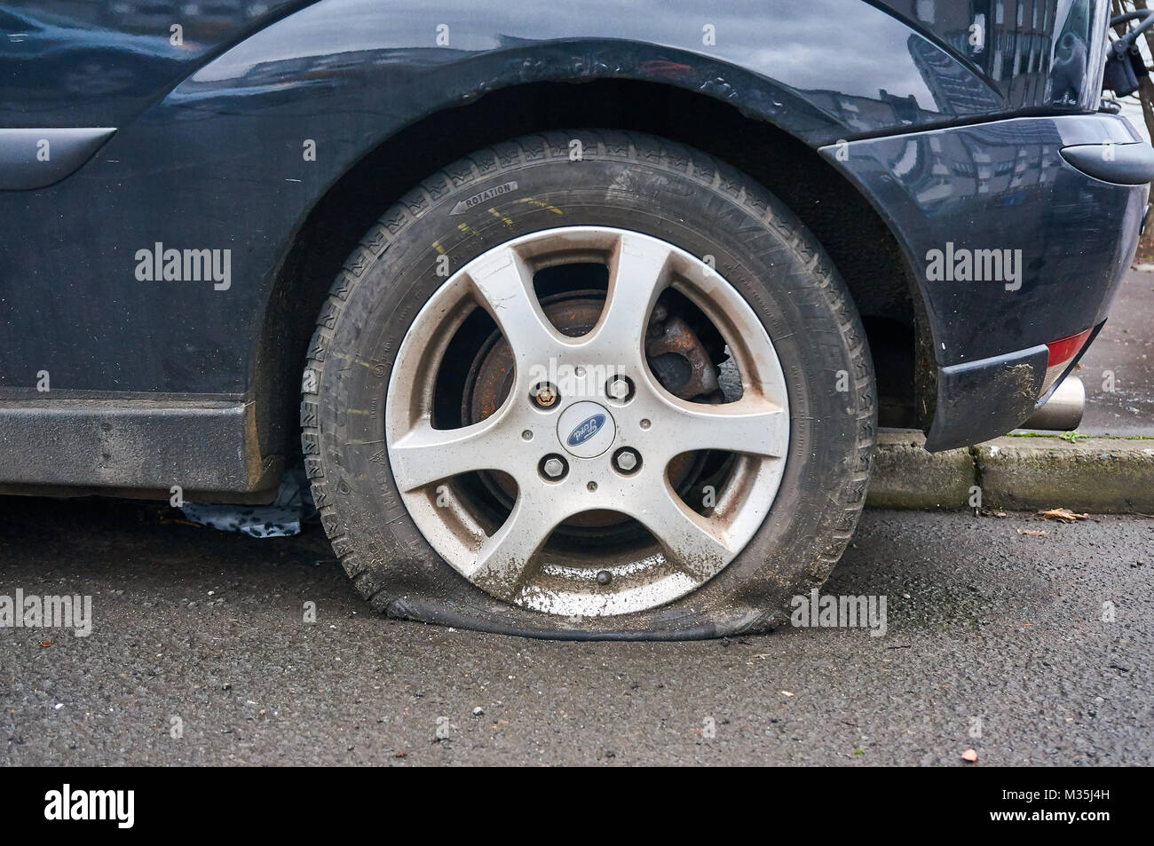 Parked car with a deflated tyre Stock Photo - Alamy