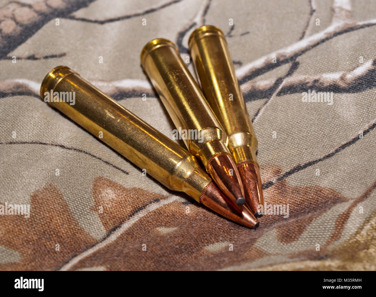 Three rifle bullets on a camouflage background Stock Photo - Alamy