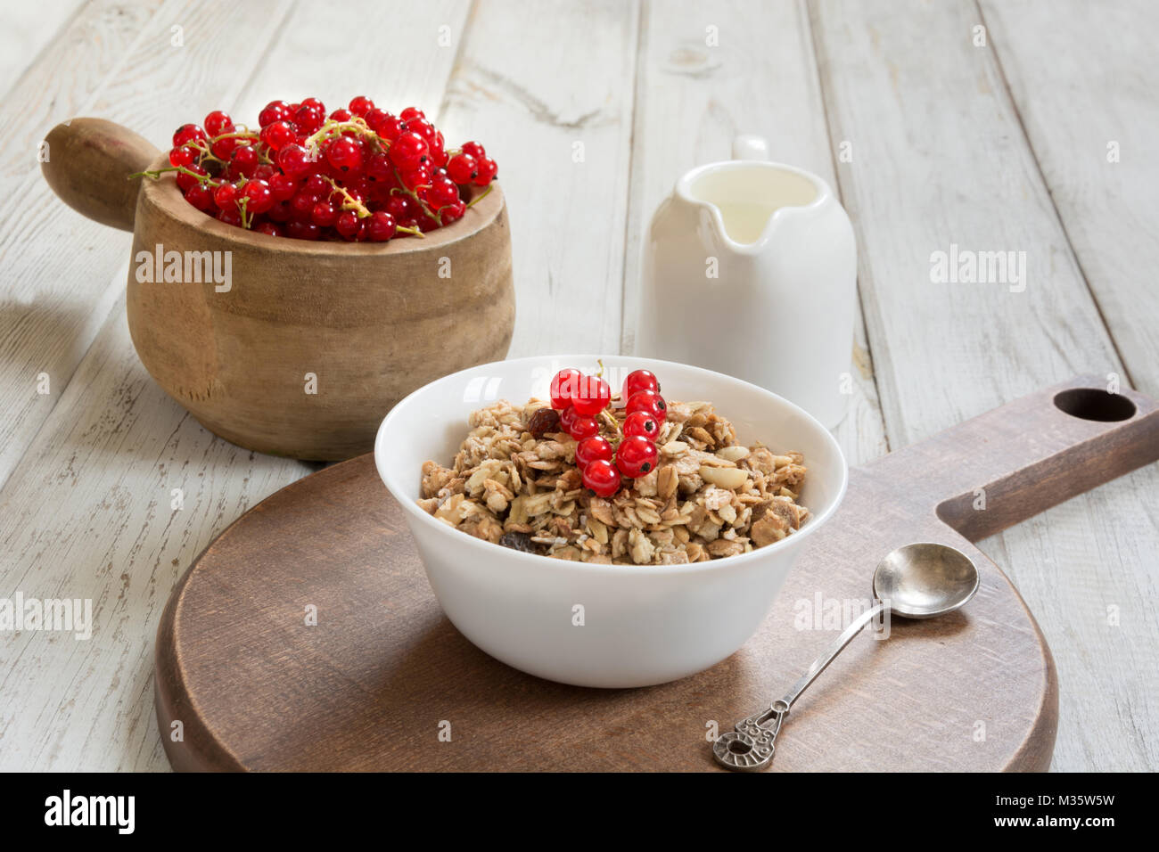 Summer healthy breakfast of granola, muesli with milk jug with red ...