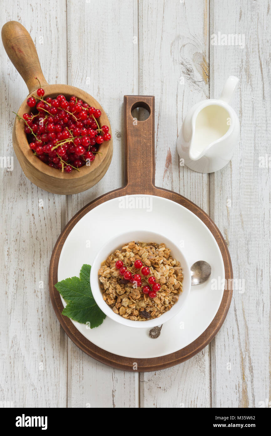 Summer healthy breakfast of granola, muesli with milk jug with red ...