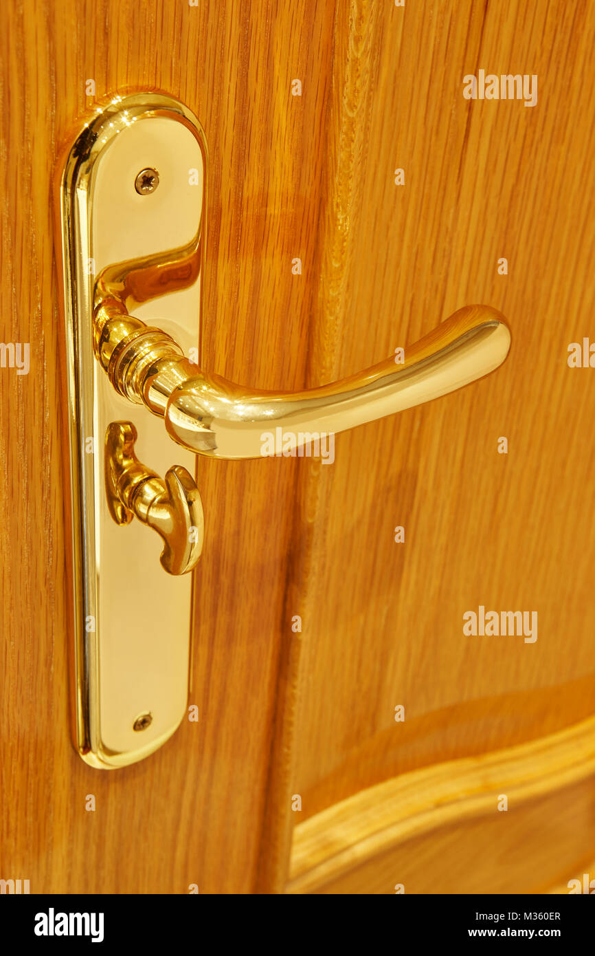 Golden door knob detail on an oak wooden door. Vertical Stock Photo - Alamy
