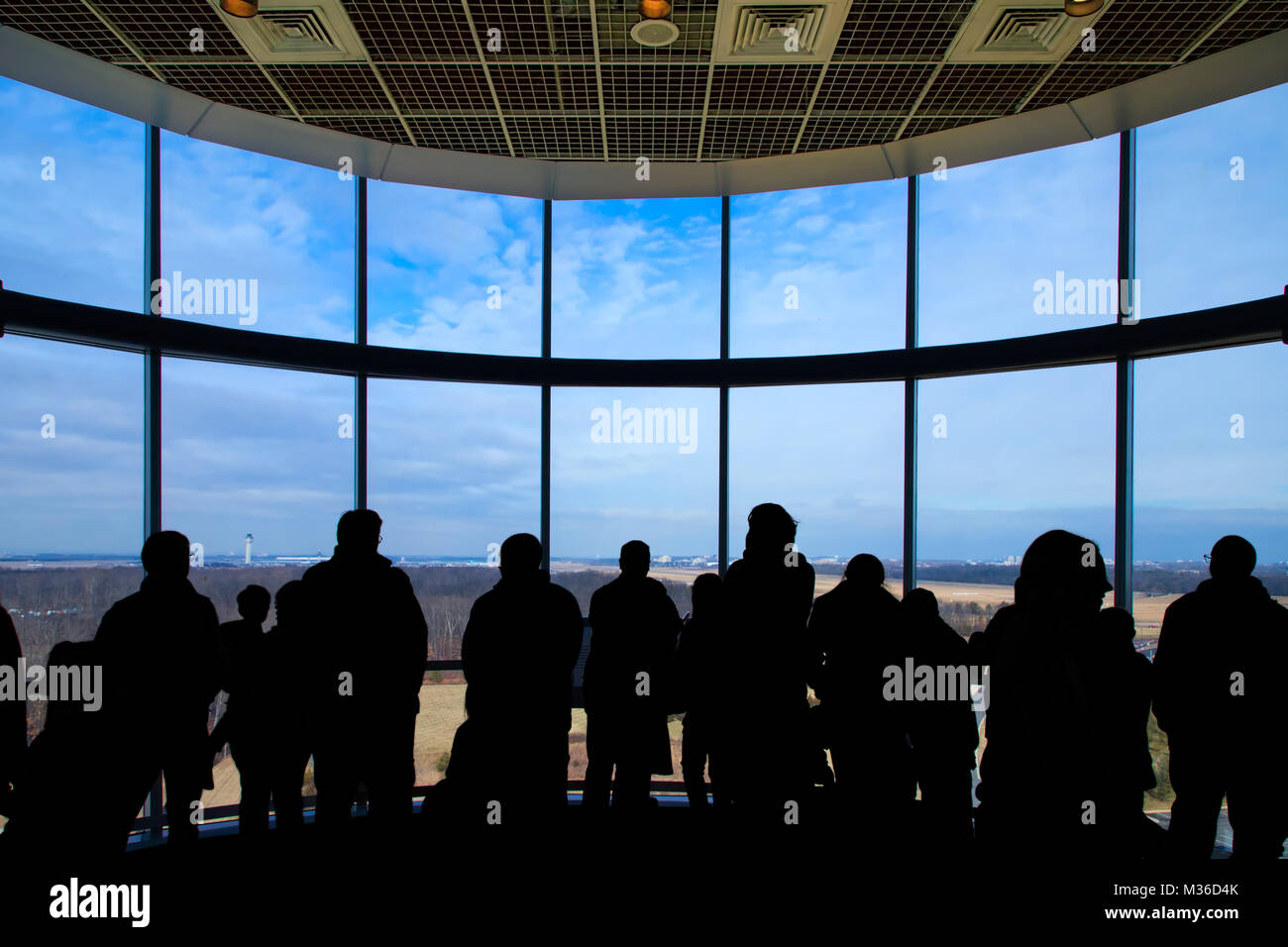 A group of people looking out a window at a runway and airport Stock ...