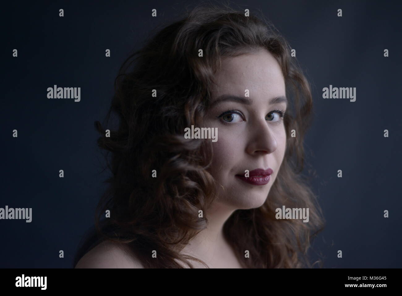 Dark Haired Vintage Styled Girl In A Red Coat With Red Lips Isolated On A Very Dark Grey