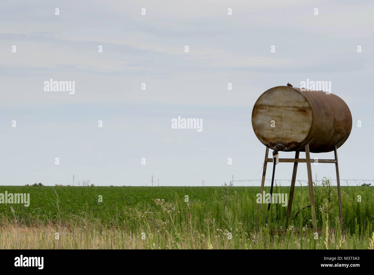 old rusty water tank and barrel on the plains under a milky white sky ...