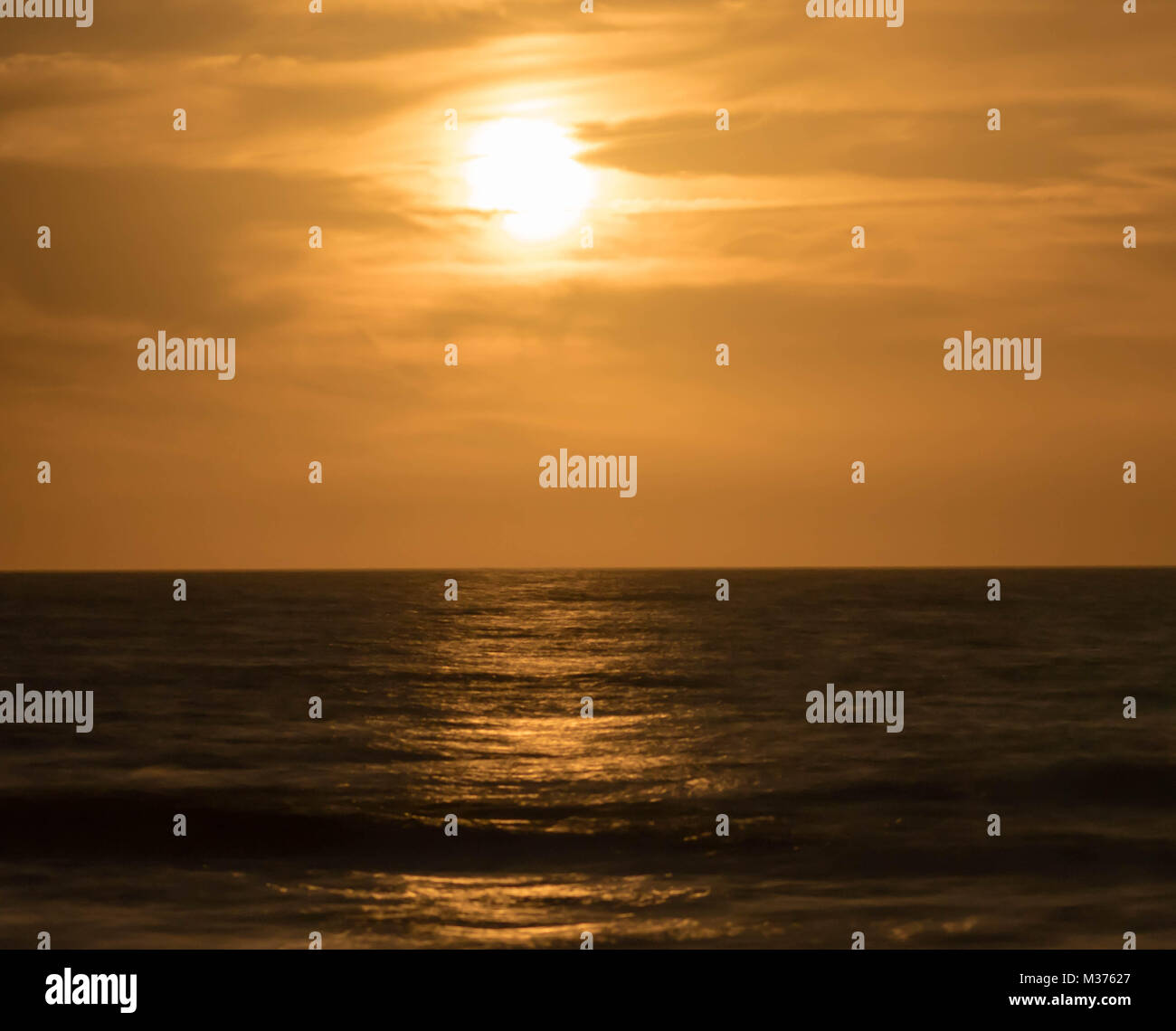 full moon rising into a warm and milky night sky over the ocean Stock ...