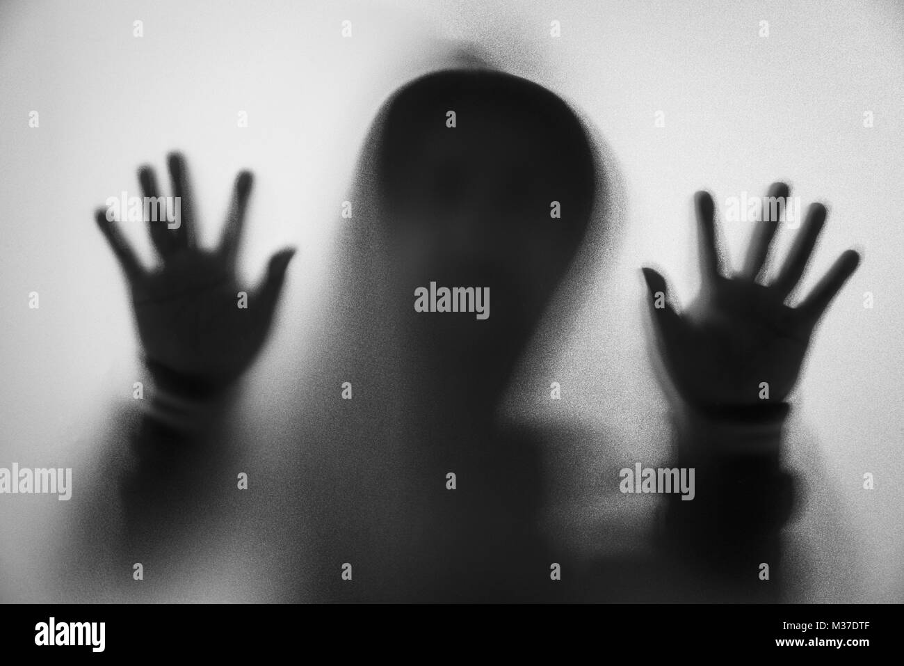 Shadow blur of horror man in jacket with hood.Hands on the glass ...