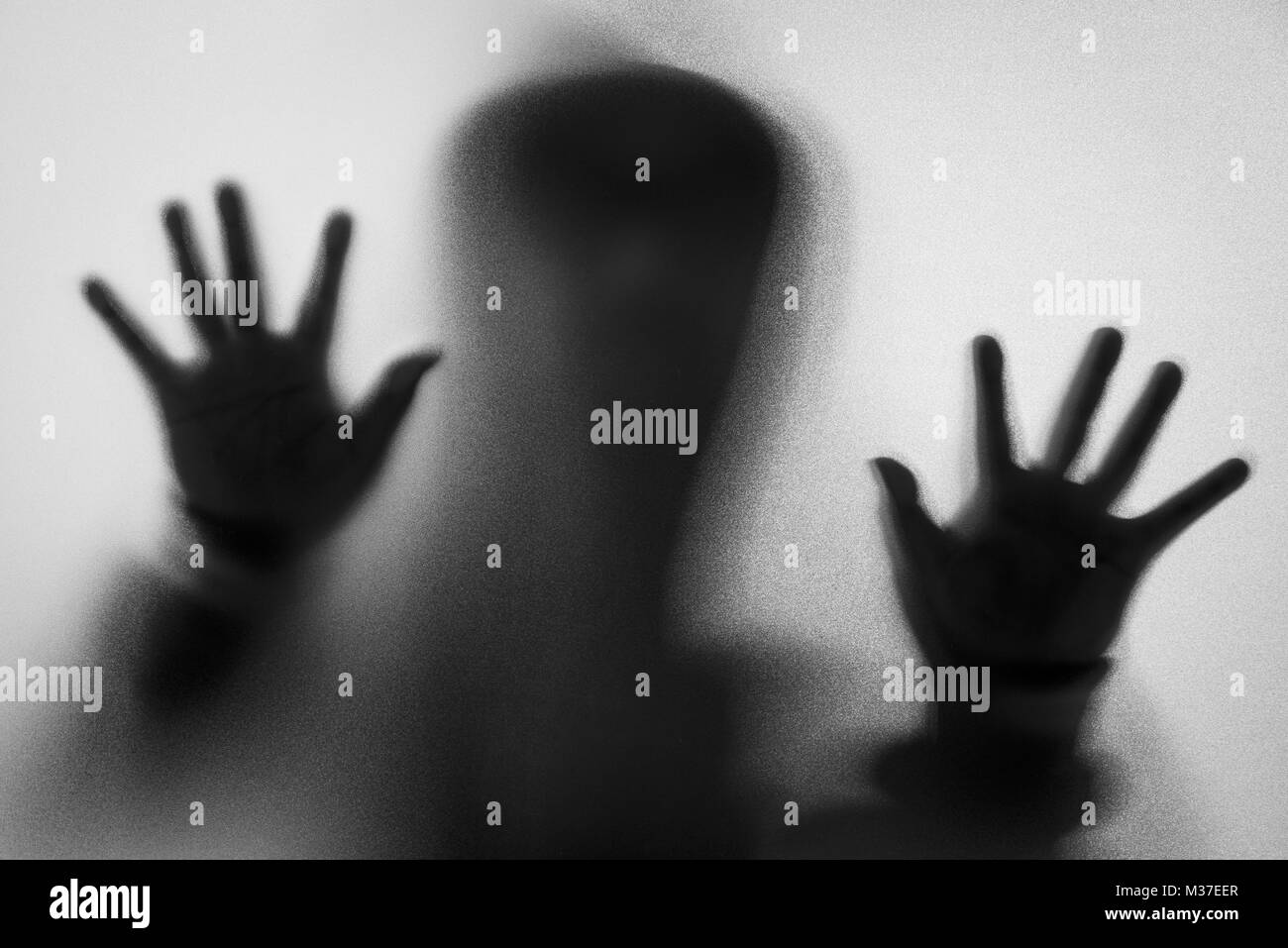 Shadow blur of horror man in jacket with hood.Hands on the glass ...