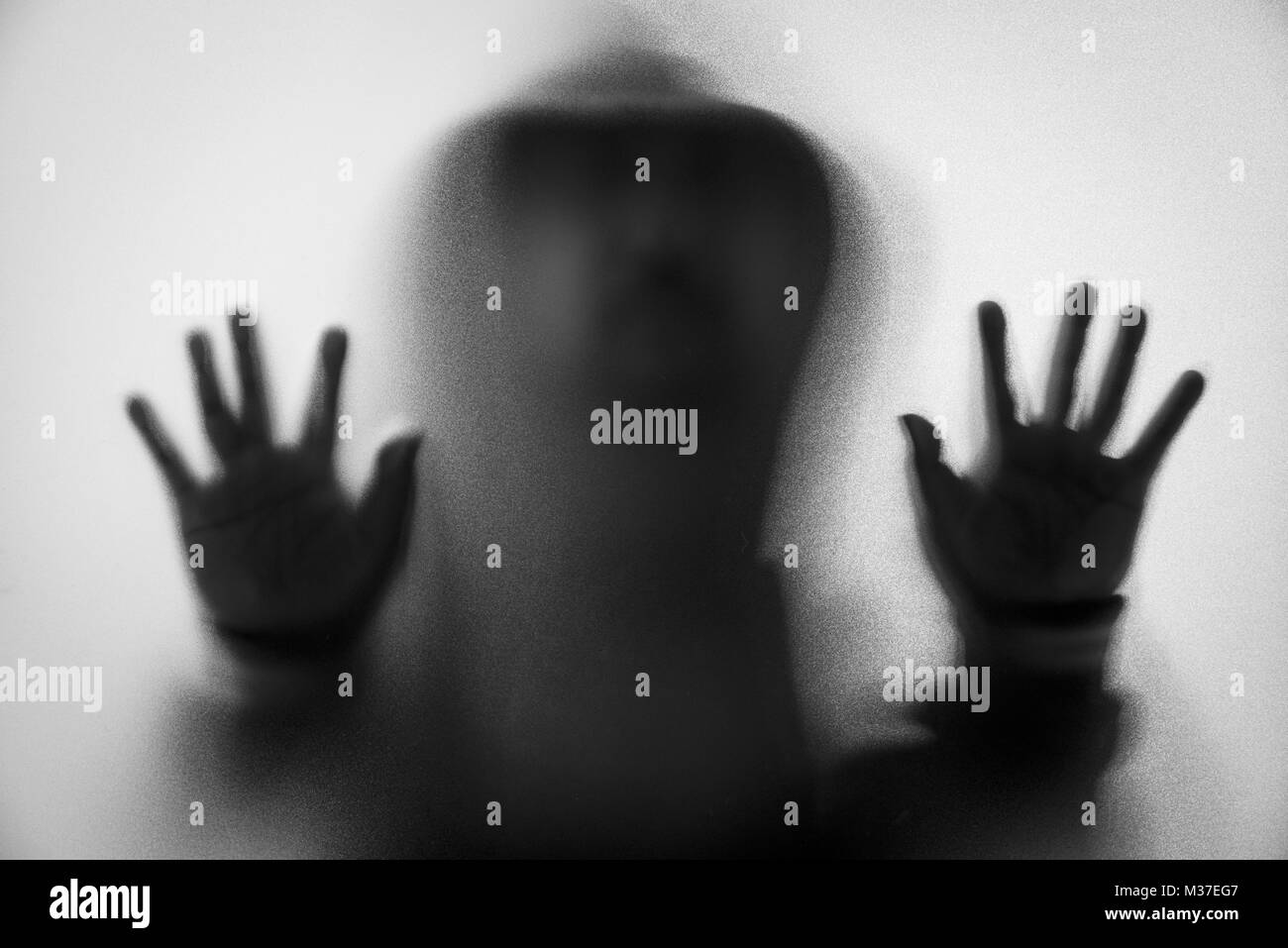 Shadow blur of horror man in jacket with hood.Hands on the glass ...