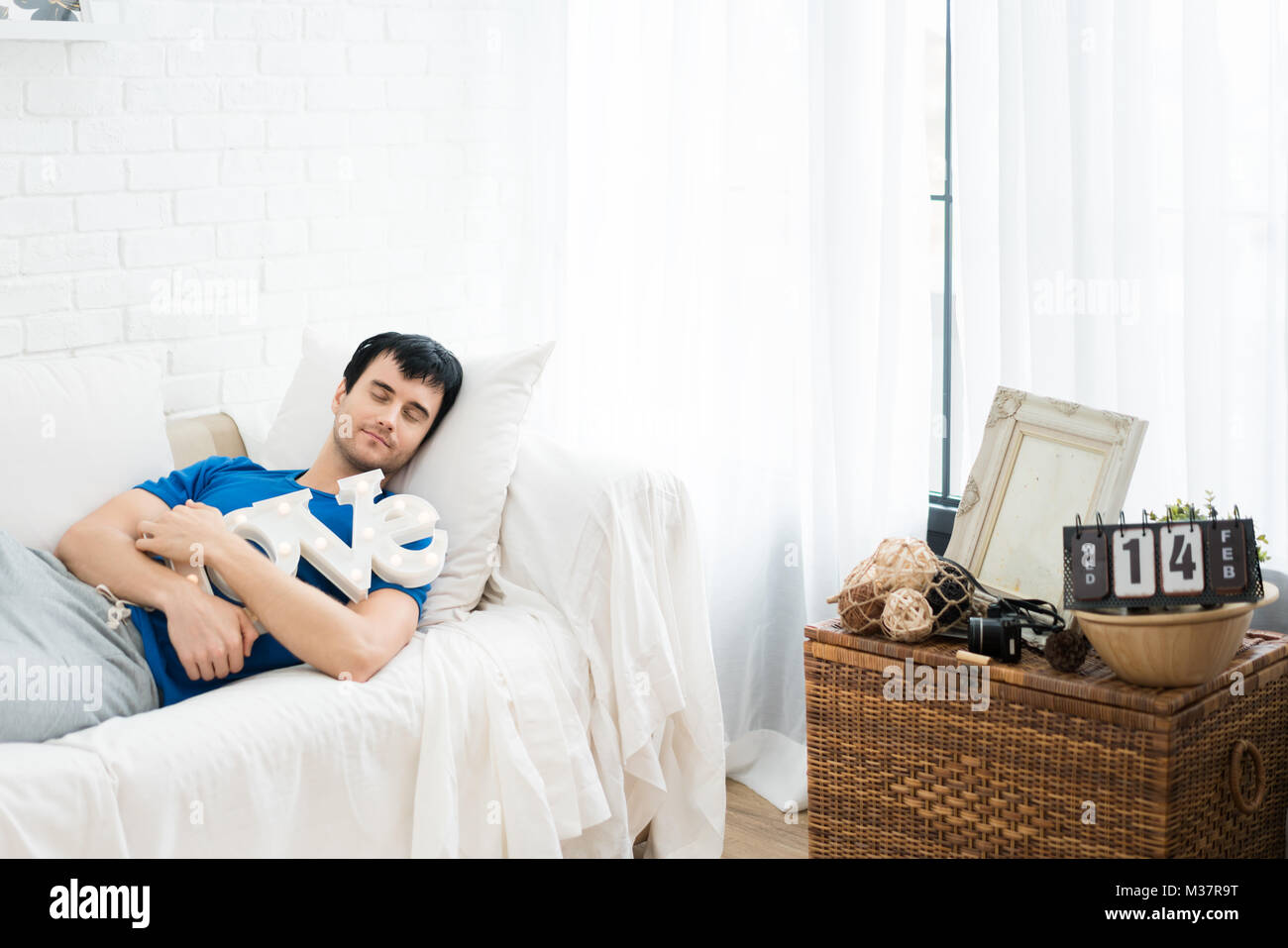 Young handsome man slepping and hugging LOVE alphabet in sofa in ...