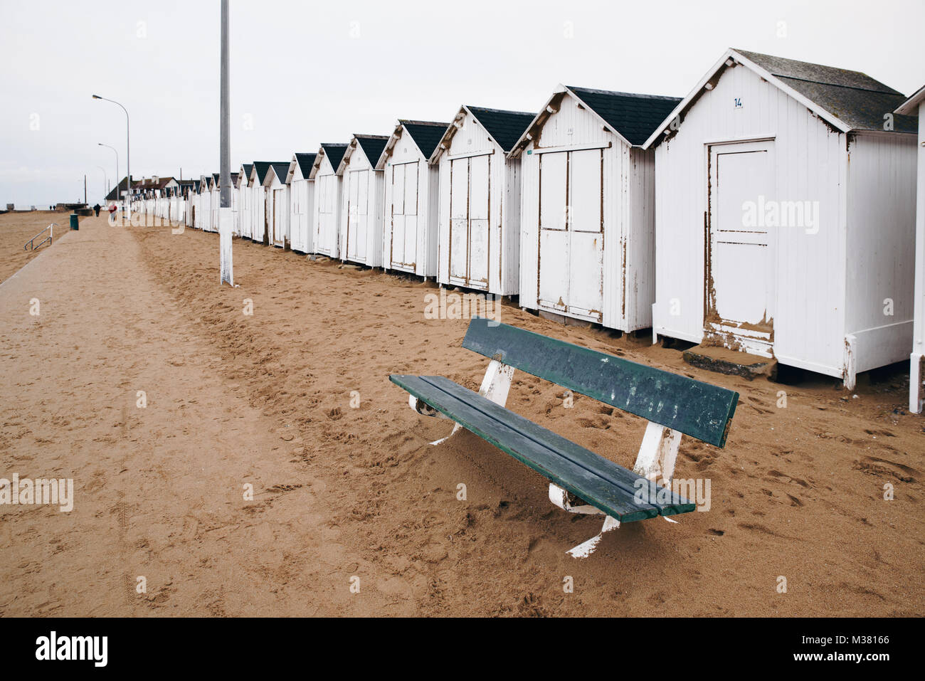 A bench and white bathing beach houses, cabins in a row on the beach ...