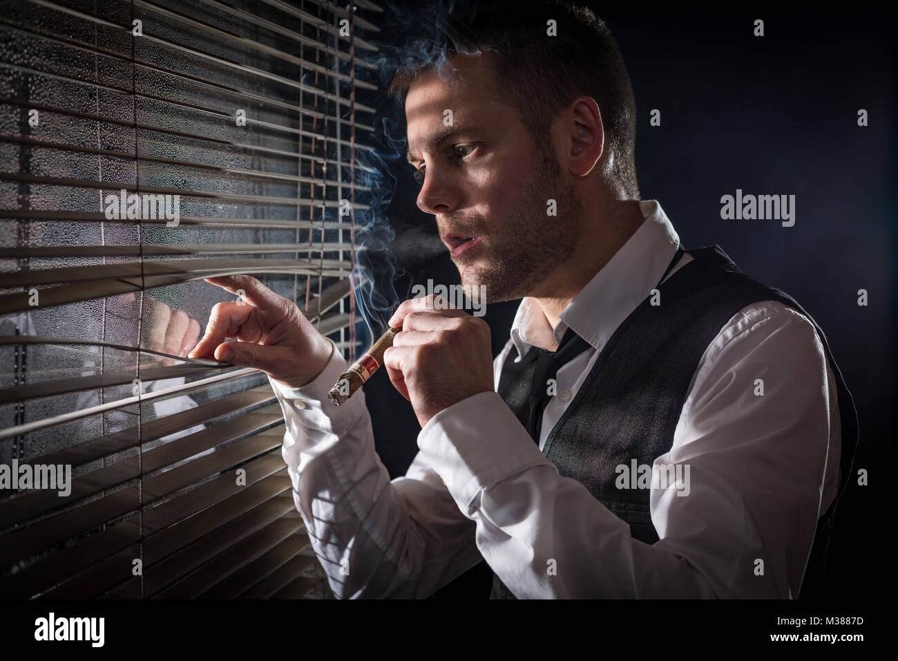 Gangster smoking a cigar while looking out the window at a car ...