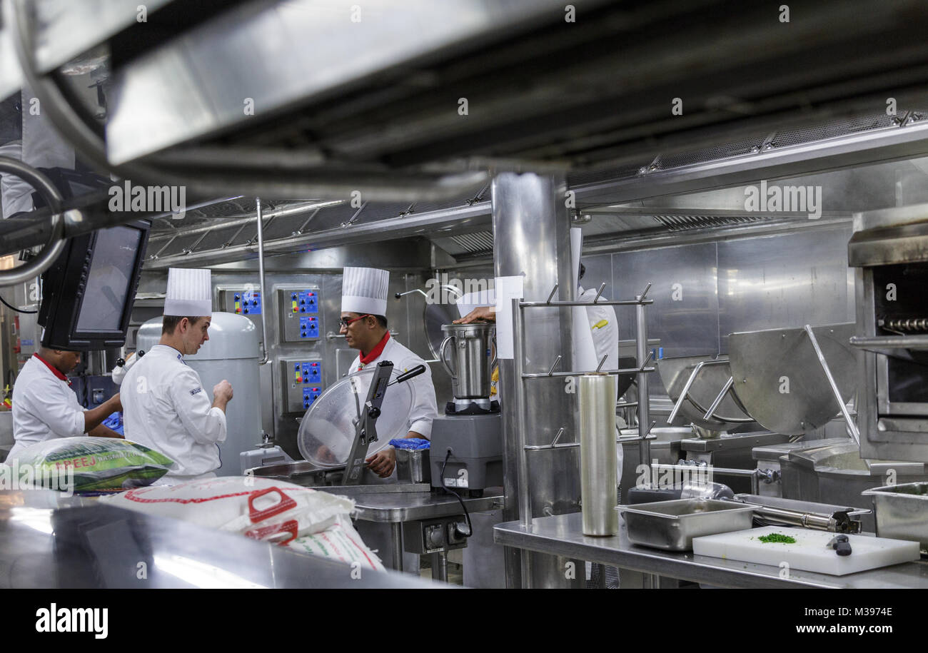 A commercial kitchen in a restaurant with cooks, food preparers and ...