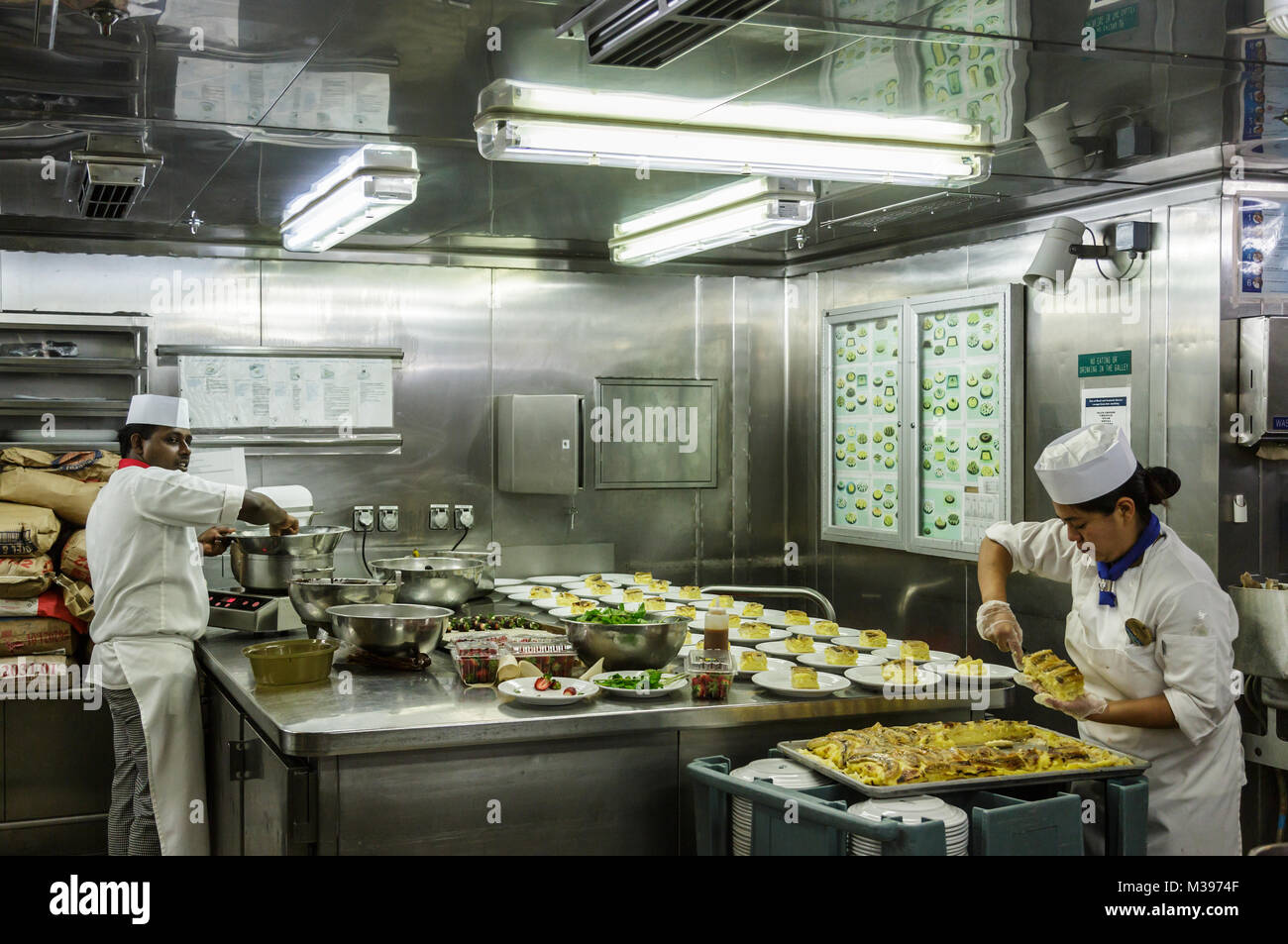 A commercial kitchen in a restaurant with cooks, food preparers and ...