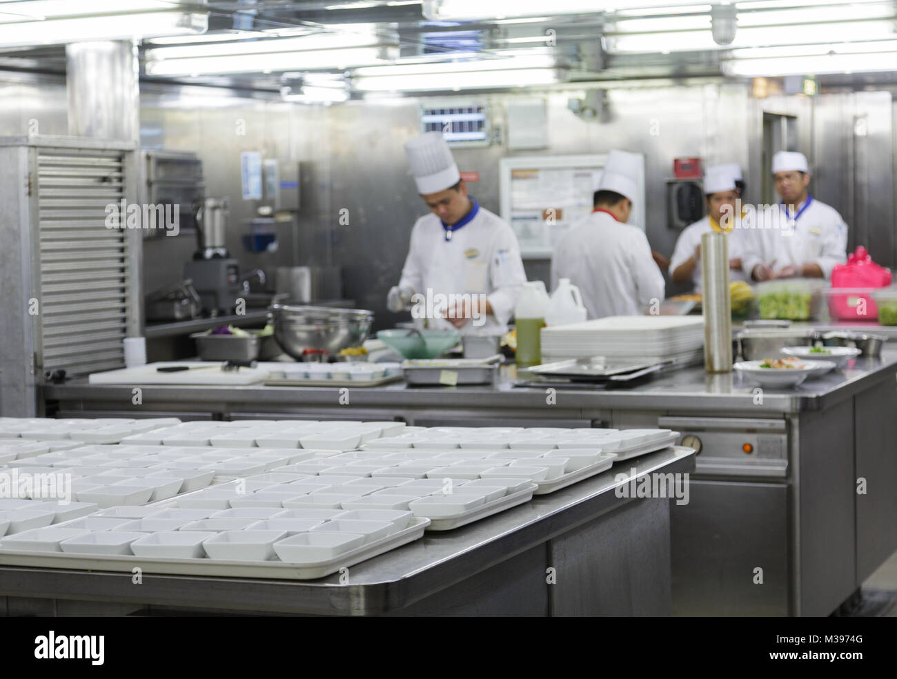 A commercial kitchen in a restaurant with cooks, food preparers and ...