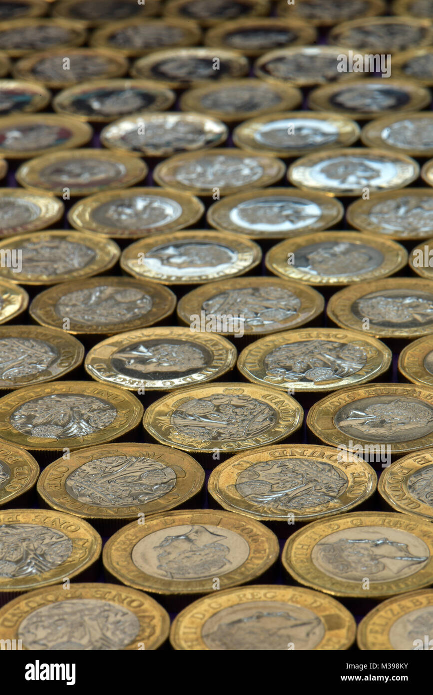 A large number of one pound coins or 1 pounds laying on a flat surface ...