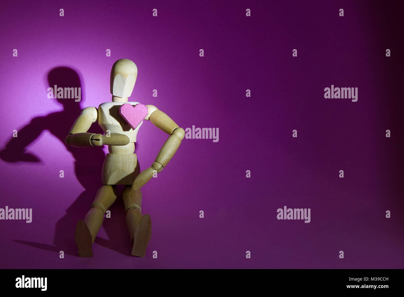 Wooden dummy and a paper box red heart shape on pink background with ...