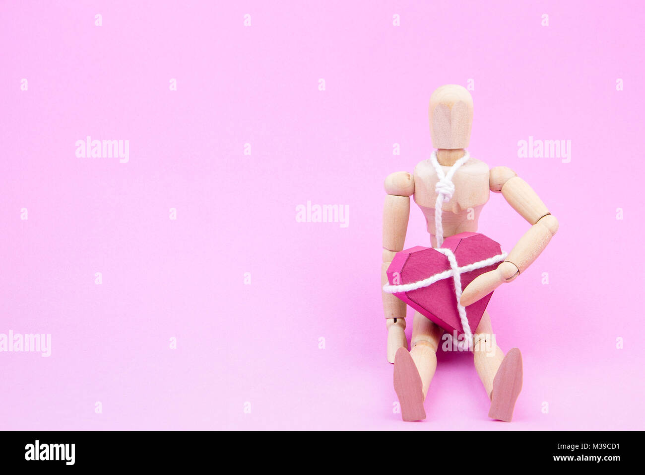 Wooden dummy chaining themselves to the paper box red heart shape on ...