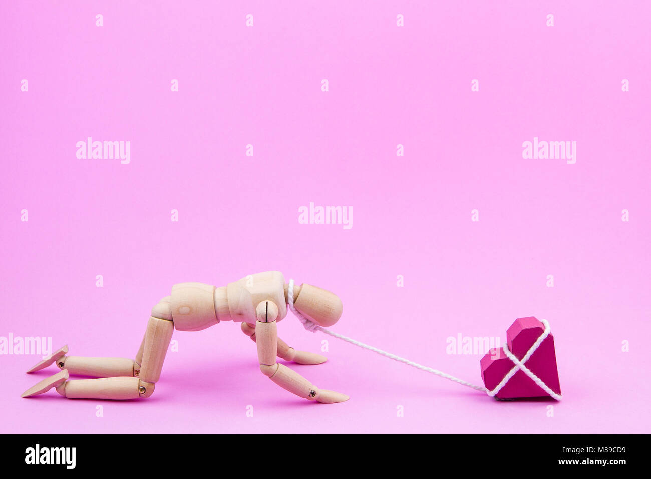 Wooden dummy chaining themselves to the paper box red heart shape on ...