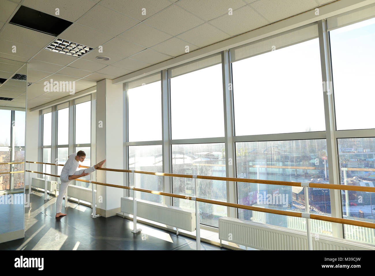 Young person making leg stretching near window Stock Photo - Alamy
