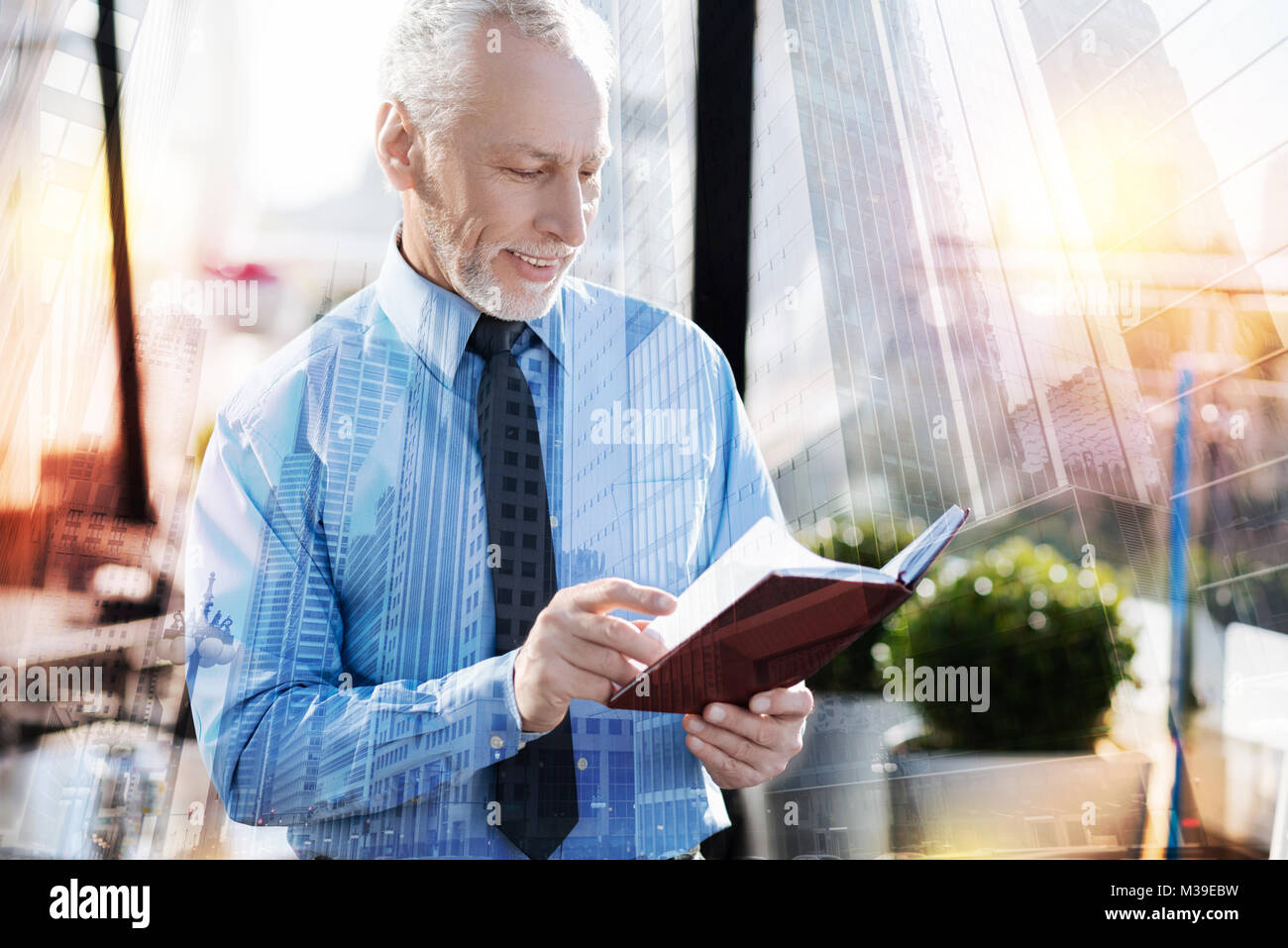 Smiling mature man standing and turning the pages of his notebook Stock ...