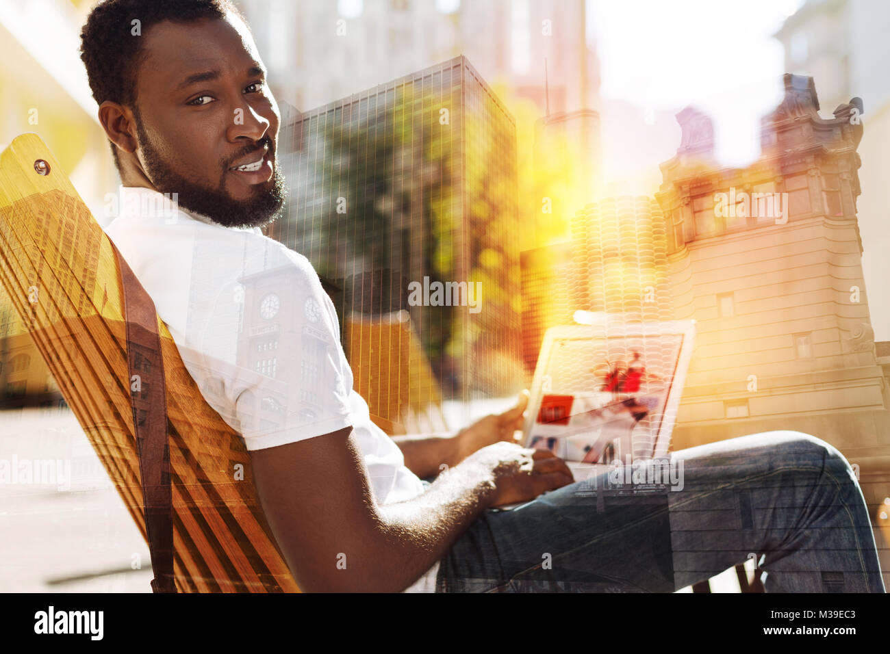 Young man turning his head and frowning while sitting with his laptop ...