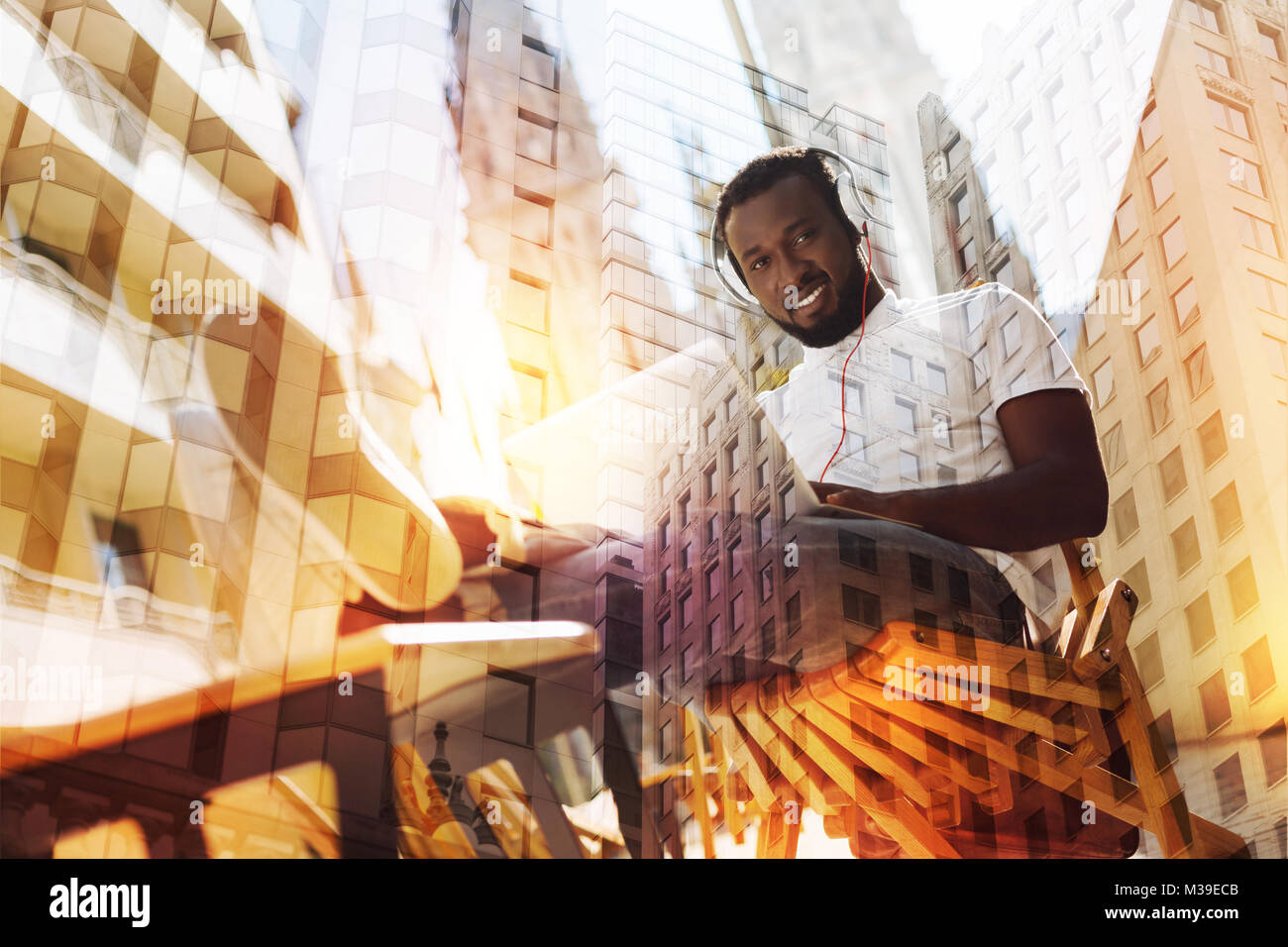 Relaxed student listening to music and smiling while sitting alone ...