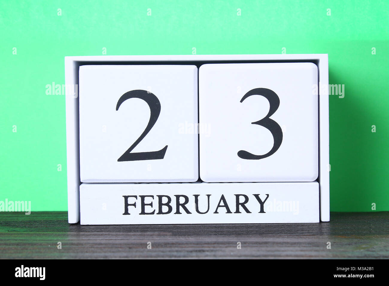 White wooden perpetual calendar with the date of February 23 on a green ...