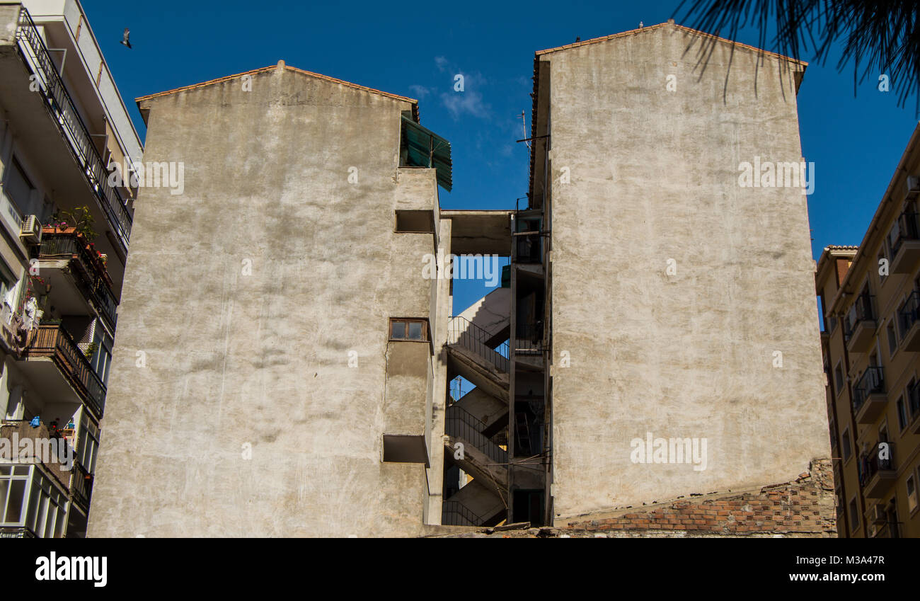 facade of two old dirty buildings with objects on their balconies ...