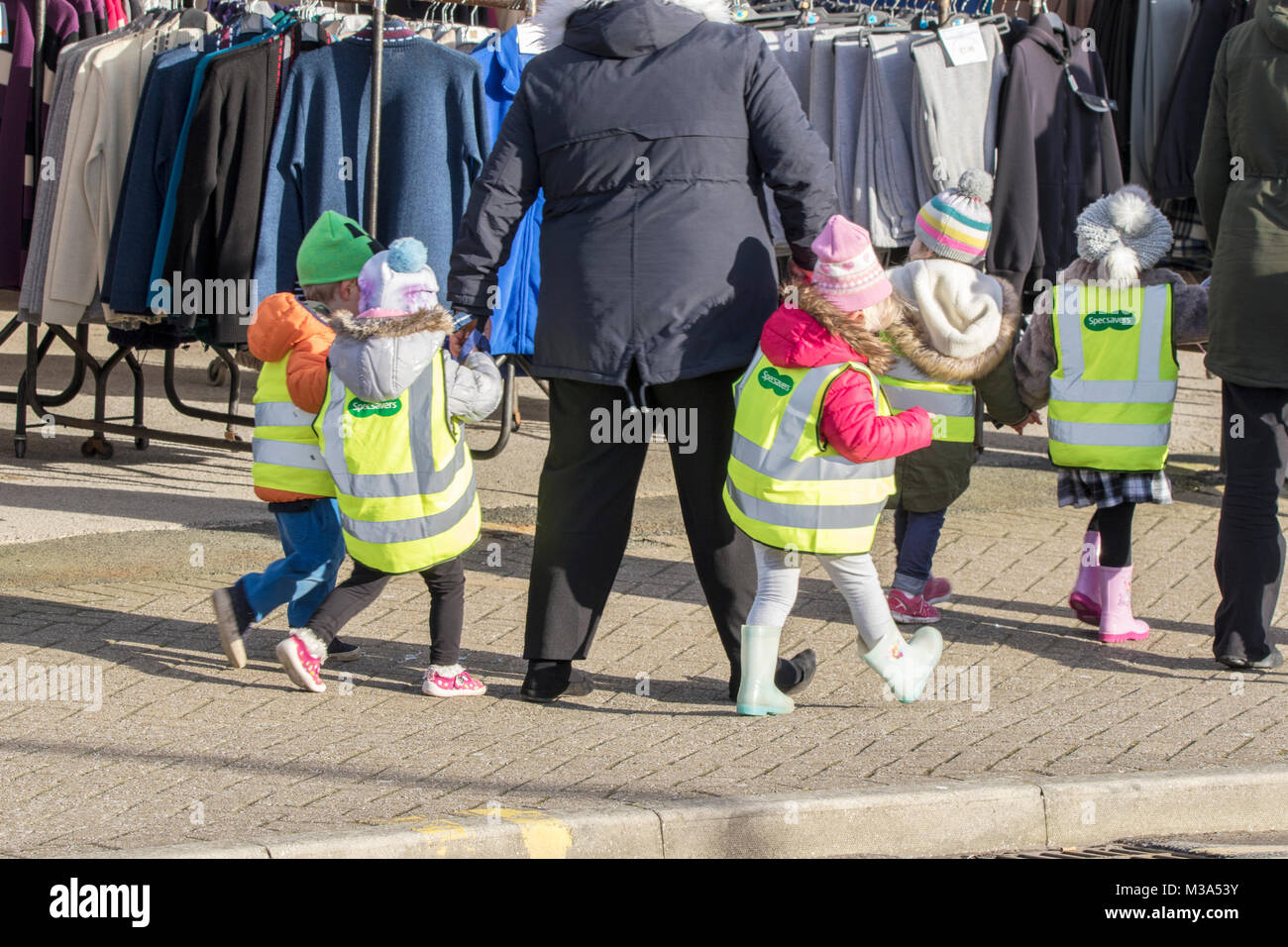 A group of escorted school children wearing hi viz vests on an outdoor ...
