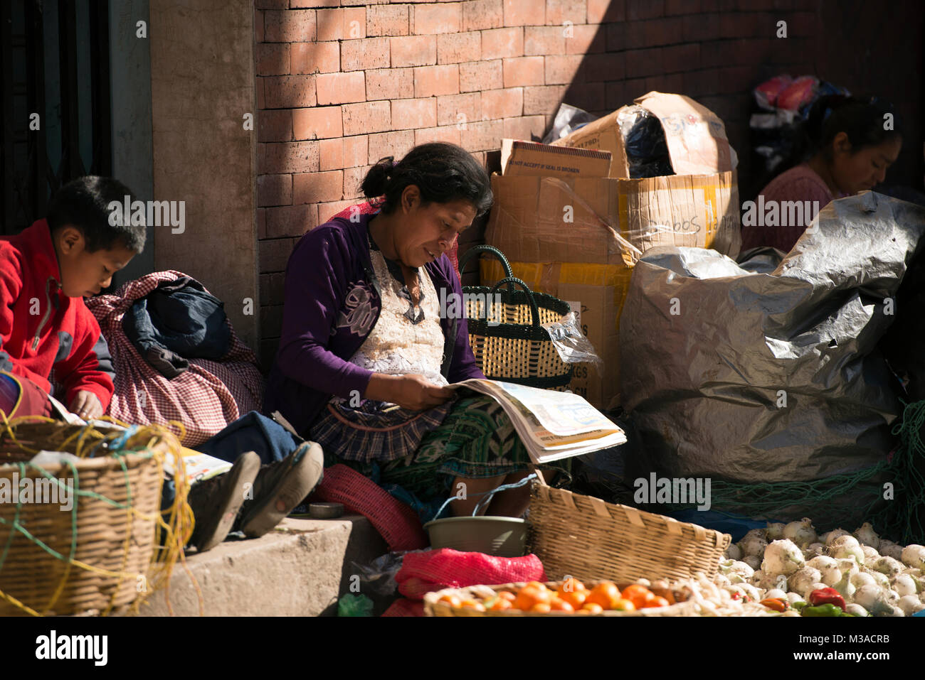 A K'iche' (Quiché) Maya woman reads a Spanish-language newspaper at the ...