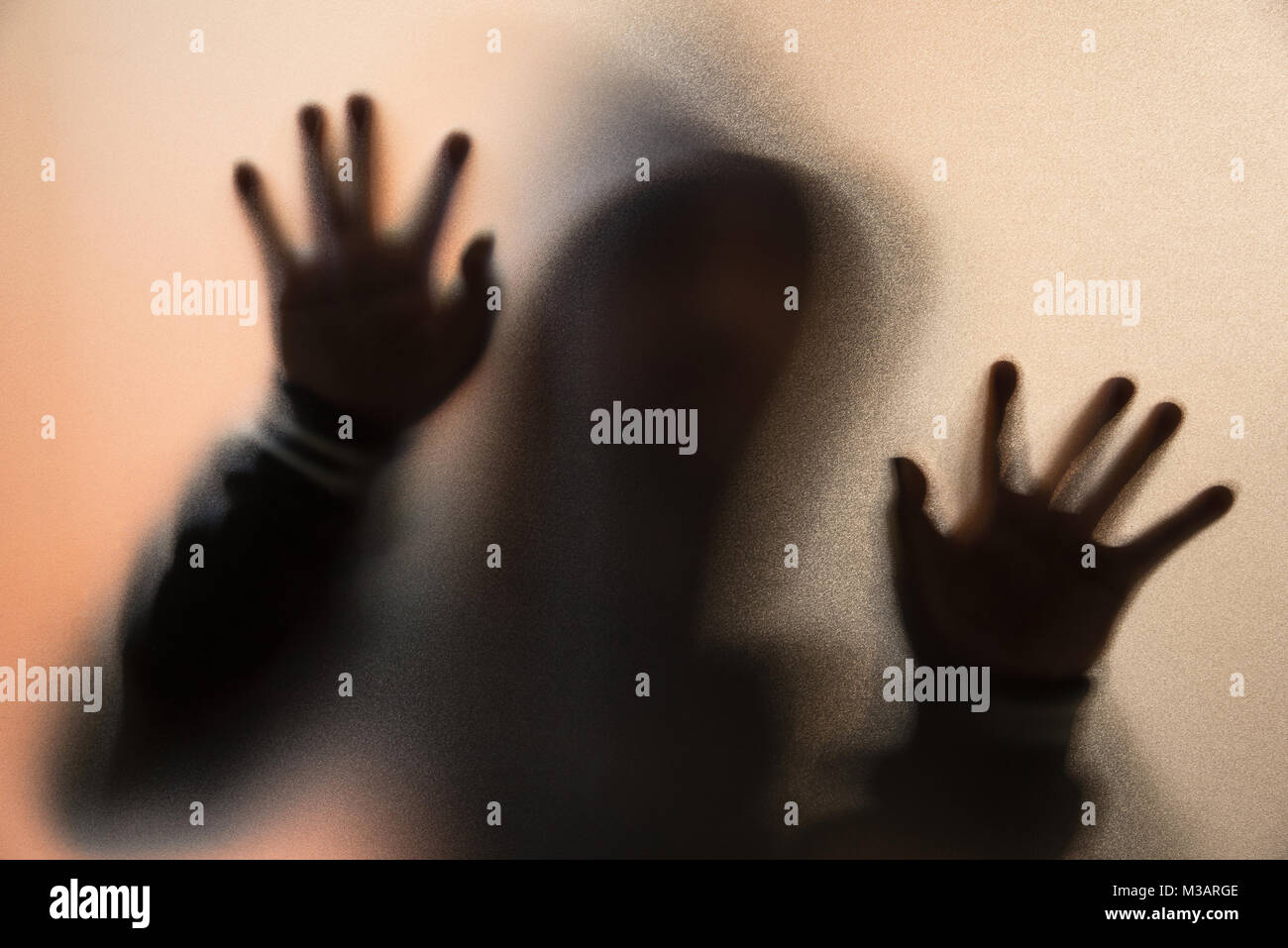 Shadow blur of horror man in jacket with hood.Hands on the glass ...